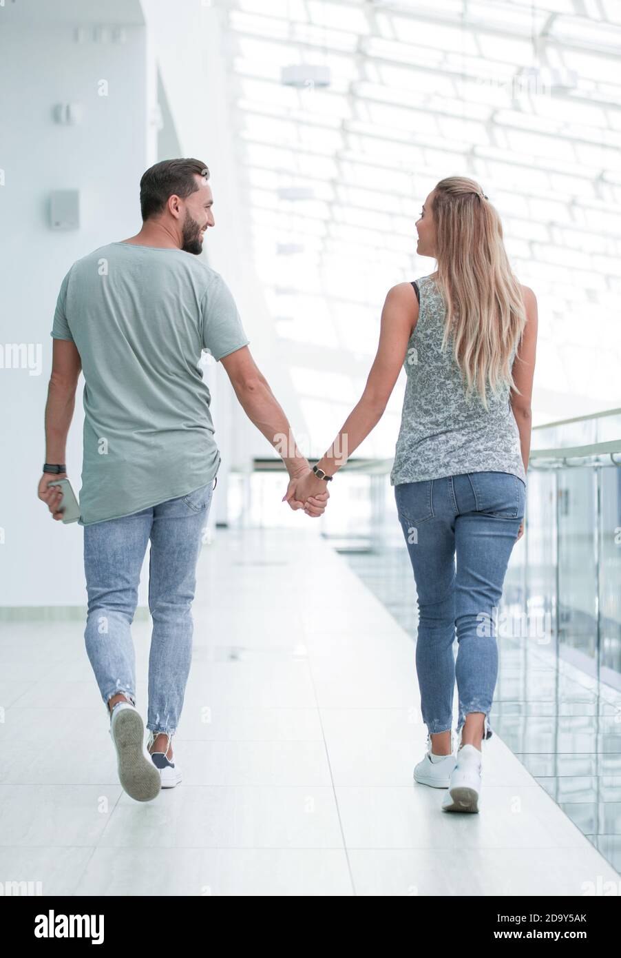 rear view.a young couple passes through the corridor of a modern ...