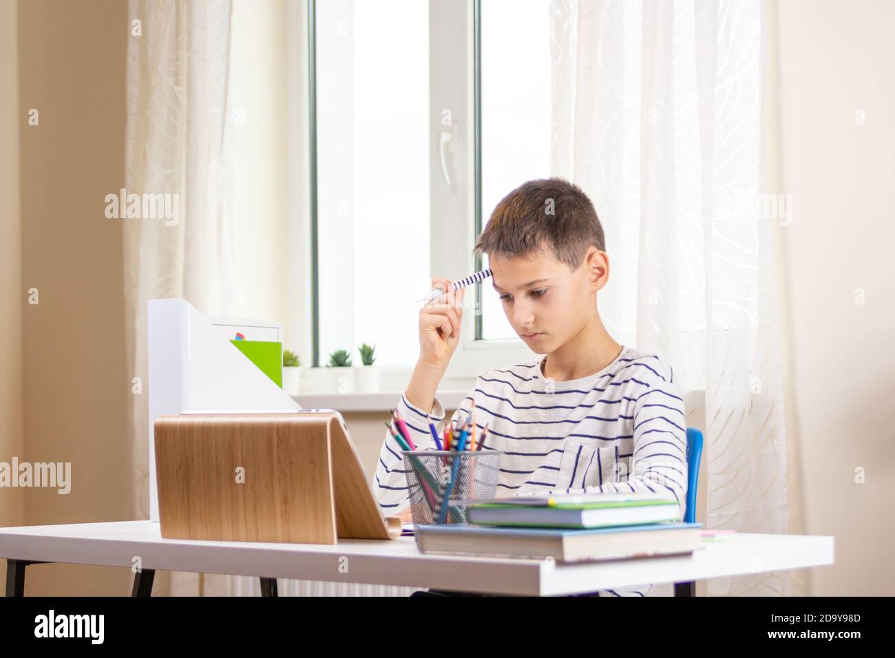 Kid with digital tablet computer writing, doing homework at white desk ...
