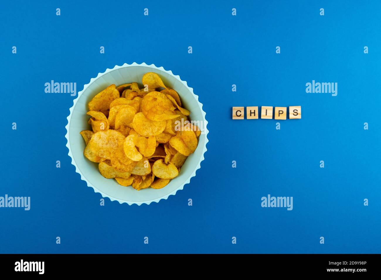 The word chips is lined with wooden letters. A bowl of potato chips on ...