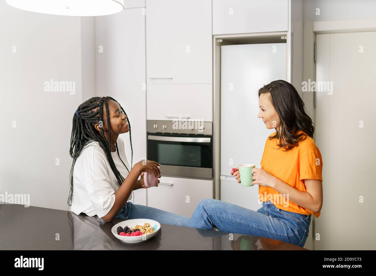 Two friends having a healthy snack while chatting at home Stock Photo ...
