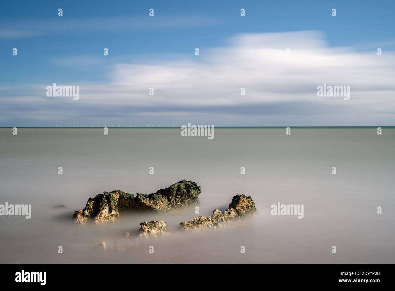 Rocks in a flat calm sea Stock Photo - Alamy