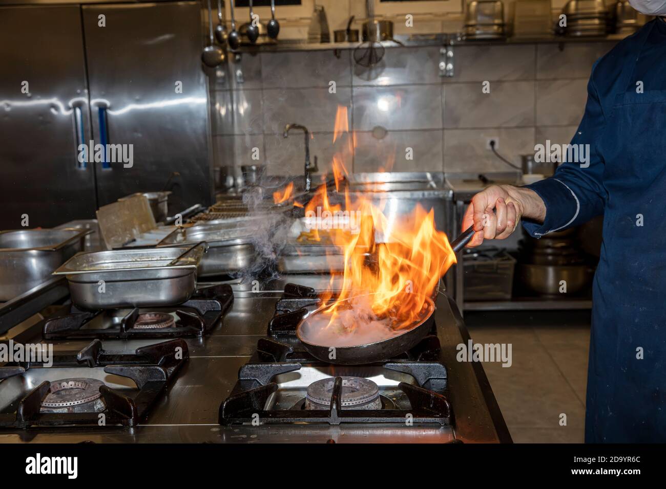 Flame in the pan. Professional Chef makes flambe for food in the ...