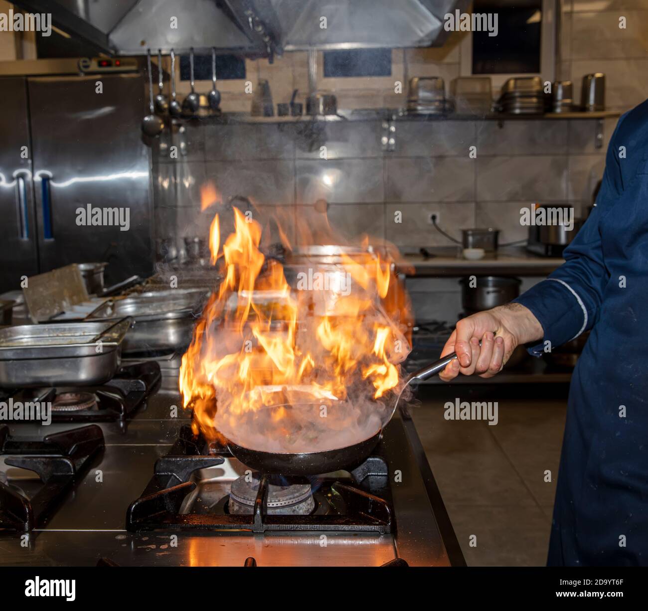 Flame in the pan. Professional Chef makes flambe for food in the ...