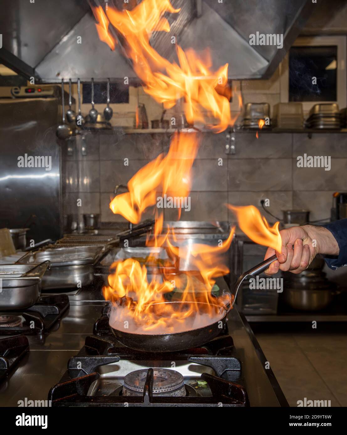 Flame in the pan. Professional Chef makes flambe for food in the ...
