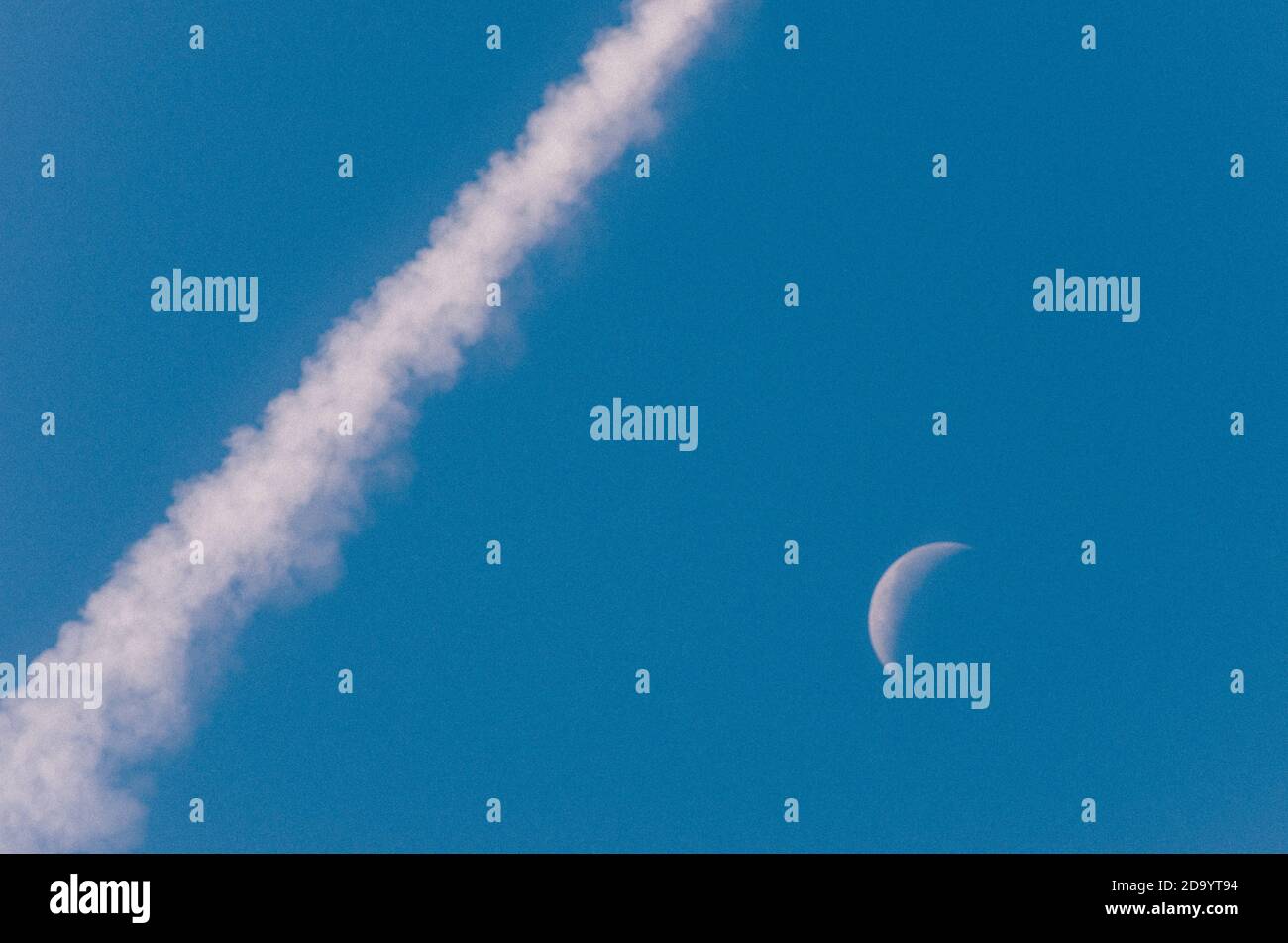 Shot of contrail and the moon during daytime Stock Photo - Alamy