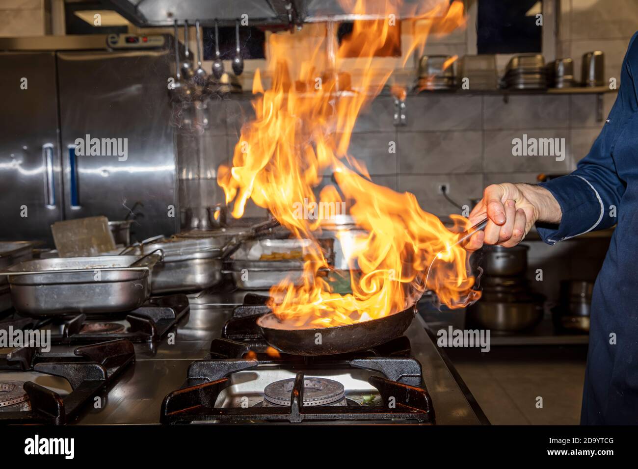 Flame in the pan. Professional Chef makes flambe for food in the ...