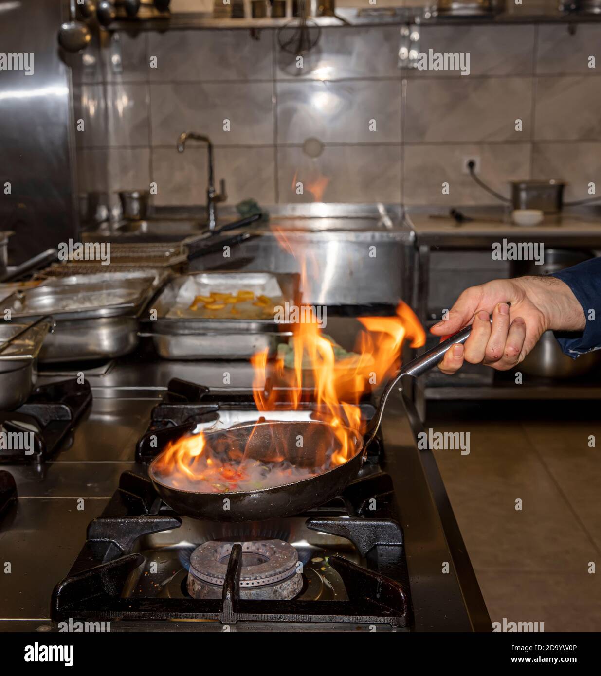 Flame in the pan. Professional Chef makes flambe for food in the ...