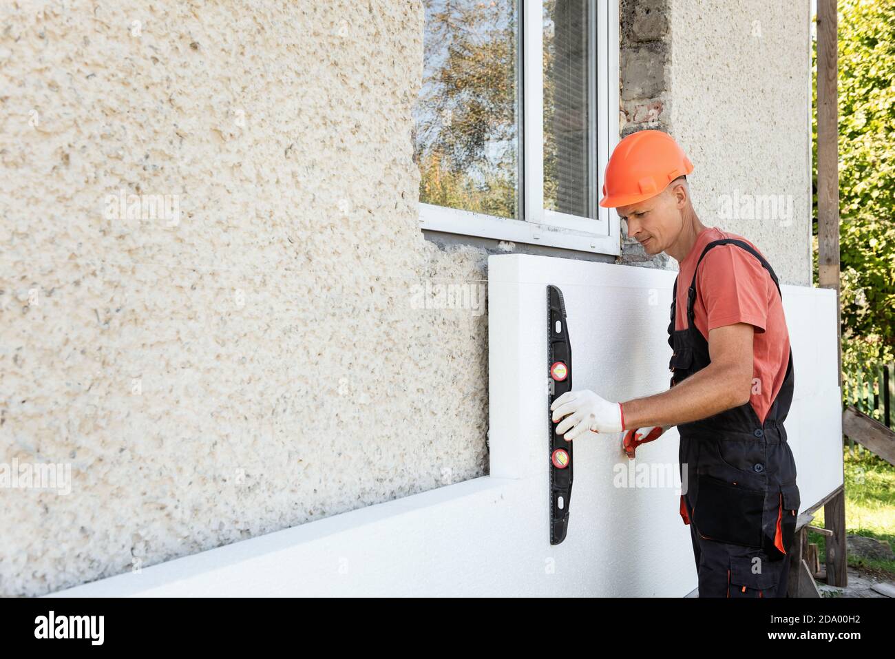 Insulation of the house with polyfoam. The worker is checking with the ...