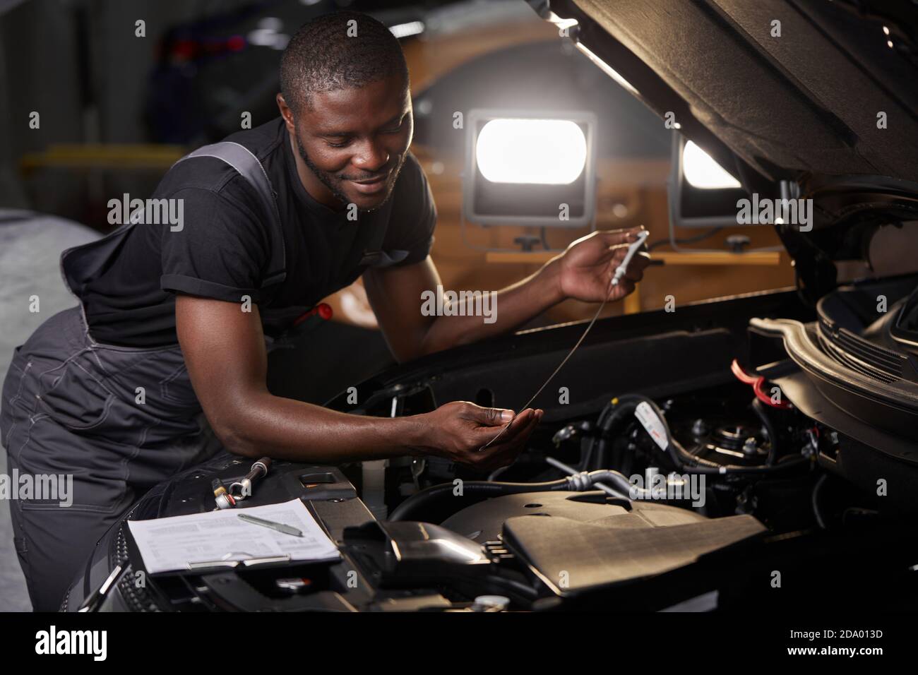 african professional auto service technician in uniform standing near ...