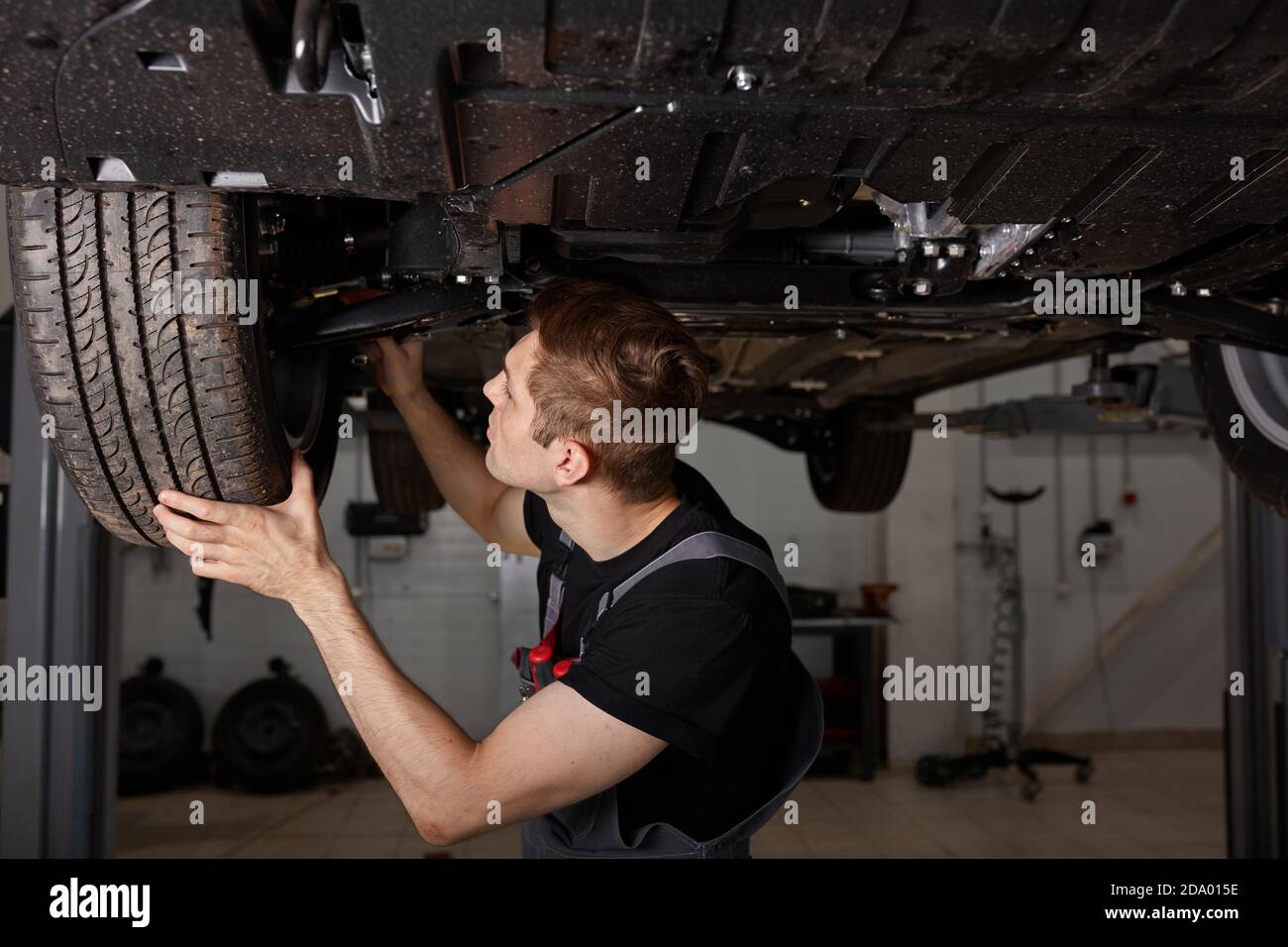 handsome caucasian male repairing bottom of car, check and examine all ...