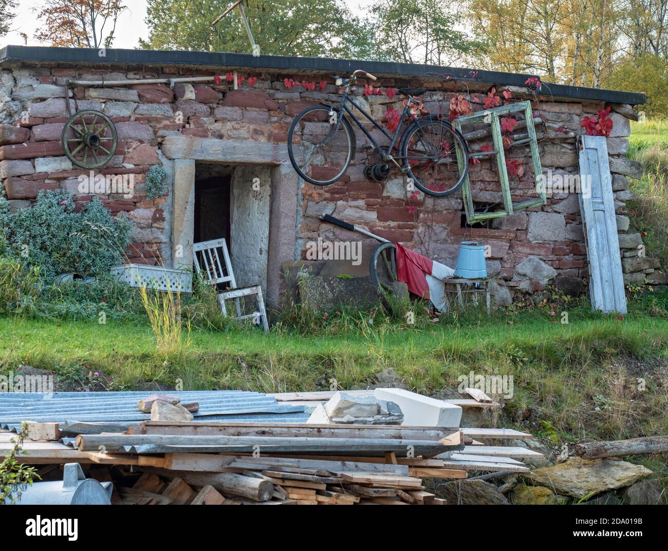 Old stony basement build in hill. Rusty old bycicle, rotting shops and ...