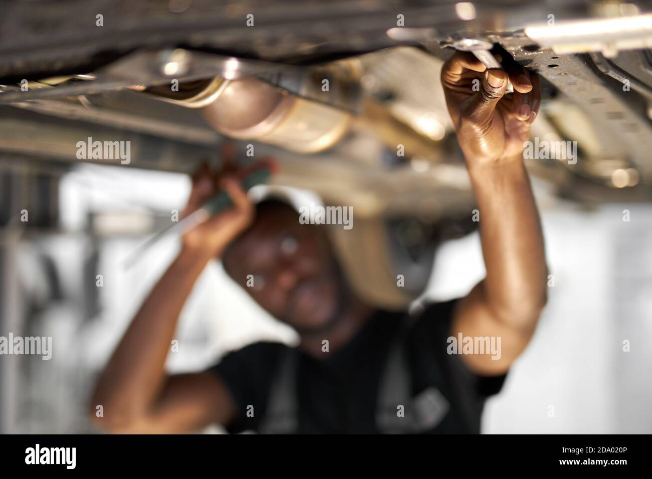 young african male car mechanic in uniform checking car in automobile ...