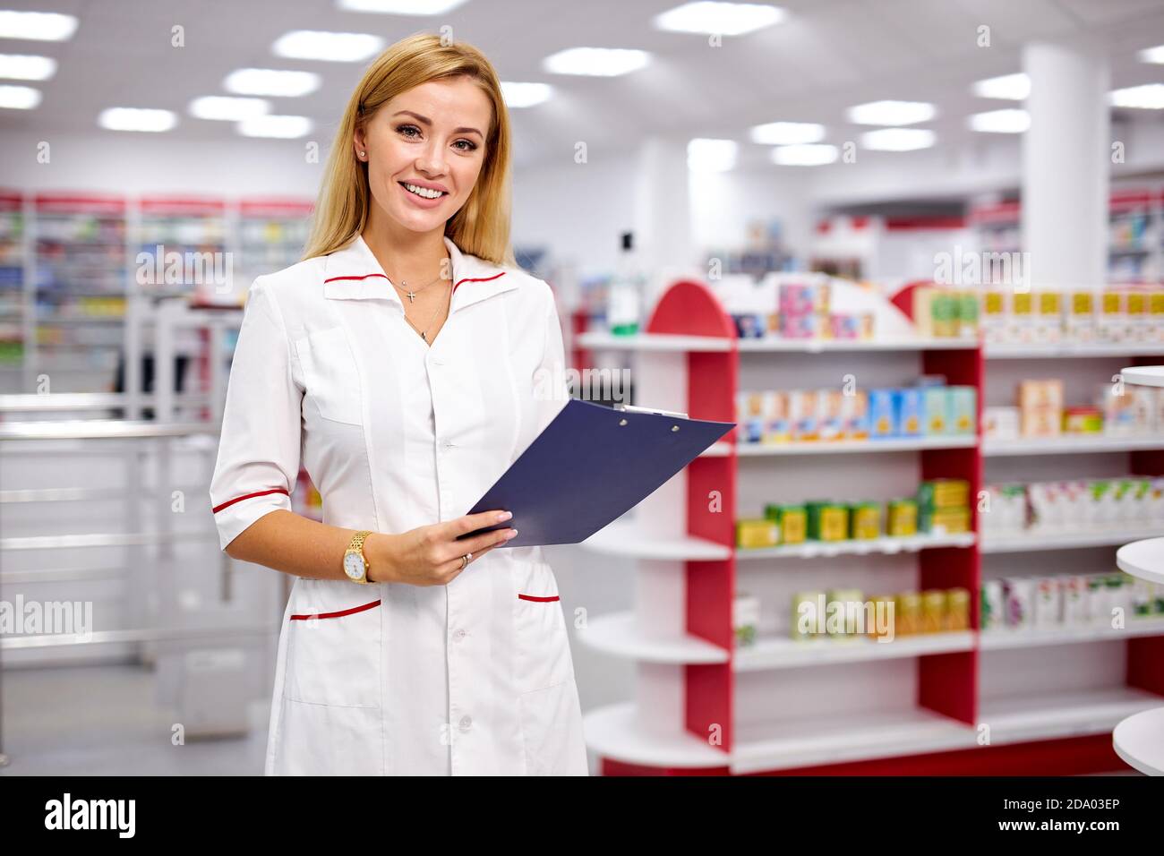 portrait of good-looking blonde pleasant female pharmacist writing on ...