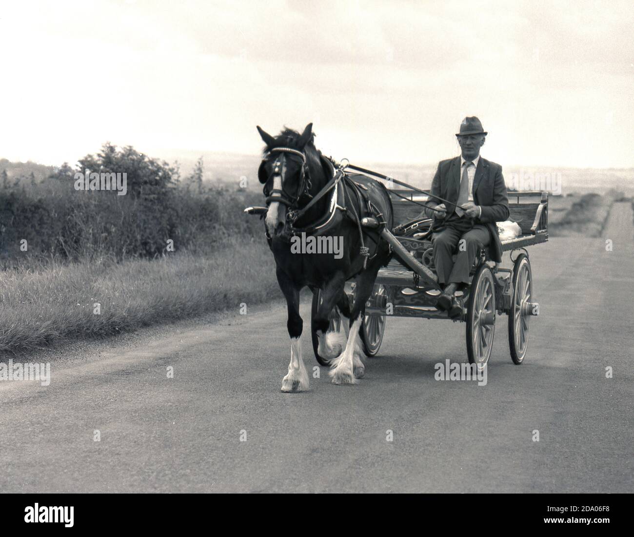 1980s, historical, a gentleman driving a cart and horse along an empty ...