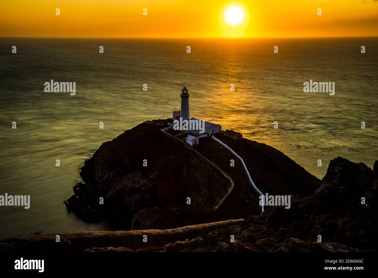 A lighthouse on cliffs with an ocean sunset (South Stack Lighthouse ...