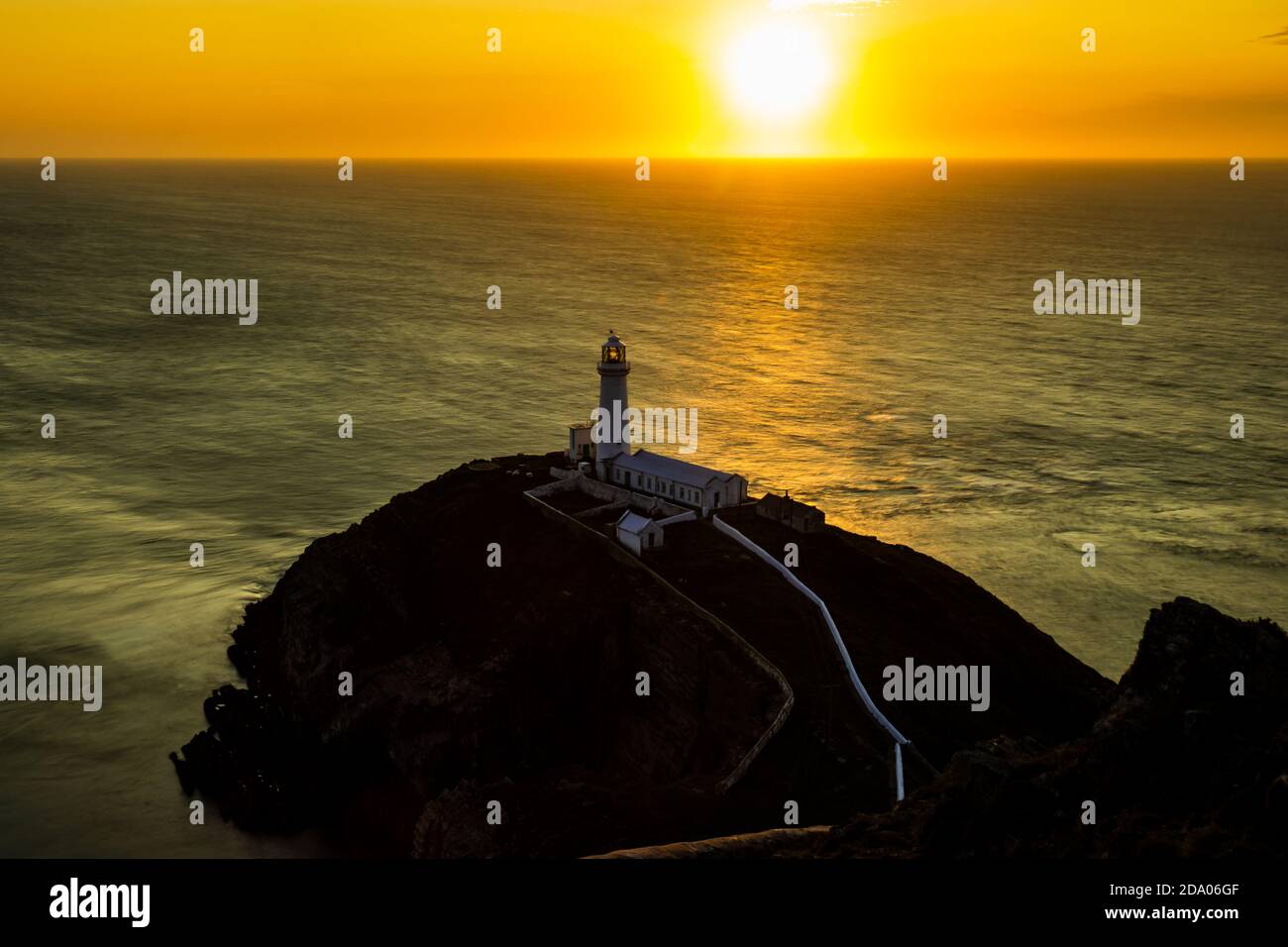 A lighthouse on cliffs with an ocean sunset (South Stack Lighthouse ...
