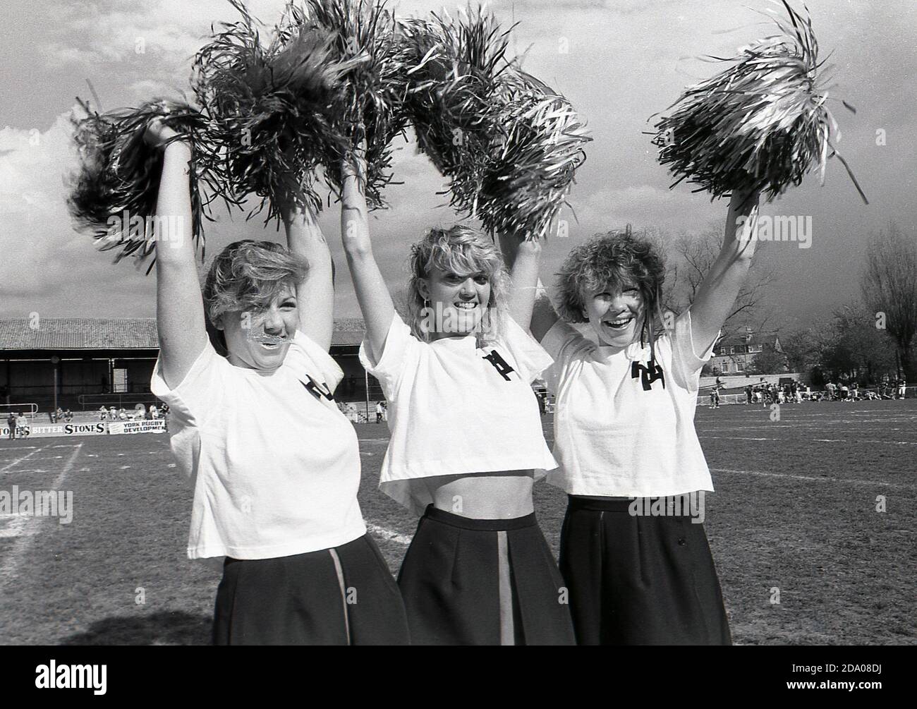 1980s, historical, three girls acting as a cheerleaders on the side of ...