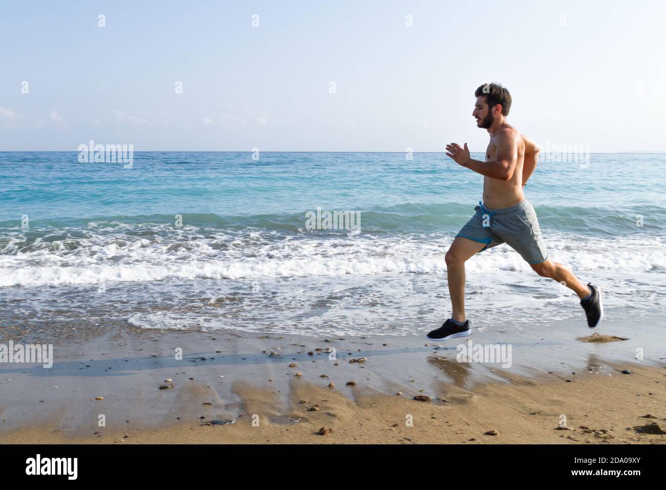 Runner sprinting towards success running on wet sand at the beach. Male ...