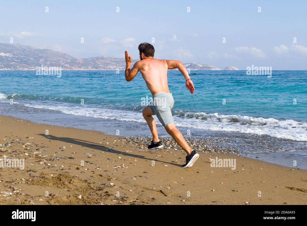 Runner sprinting towards success running on wet sand at the beach. Male ...