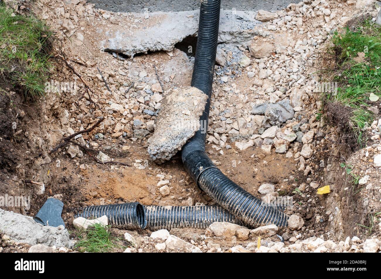 a ditch hole at a construction site with black flexible sewage pipes ...