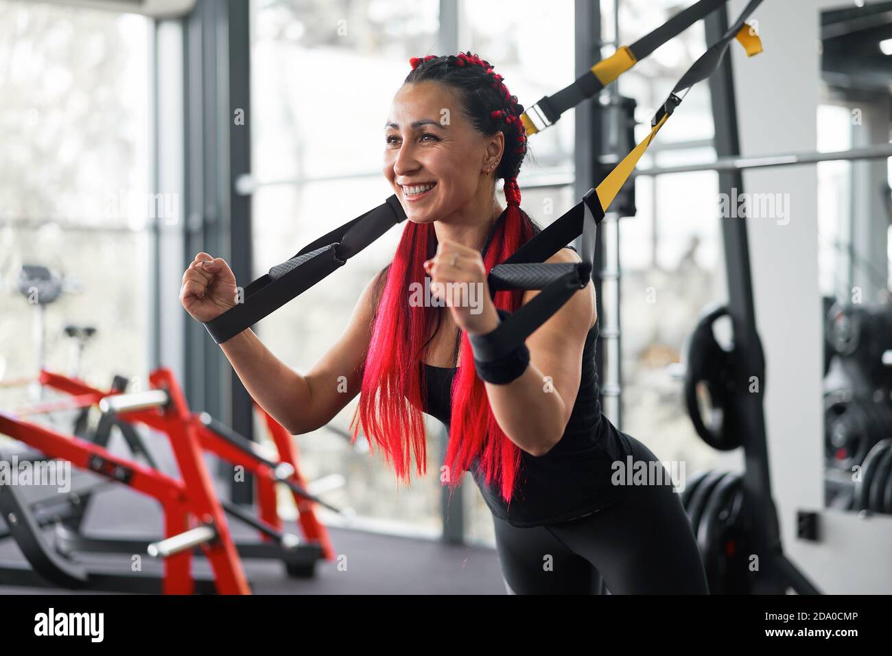 Athlete woman training exercising with suspension system indoor gym ...