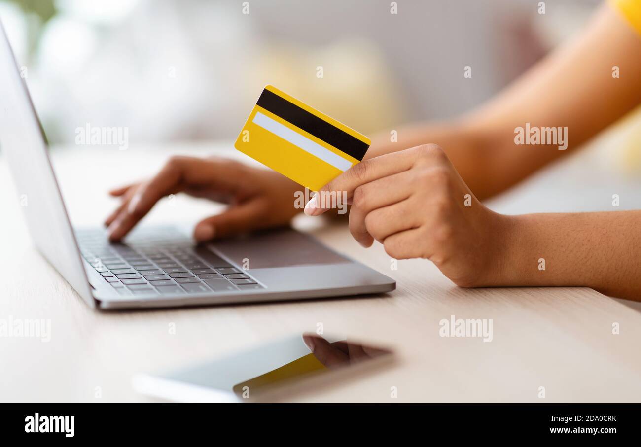 Black female customer using laptop and credit card at home Stock Photo ...