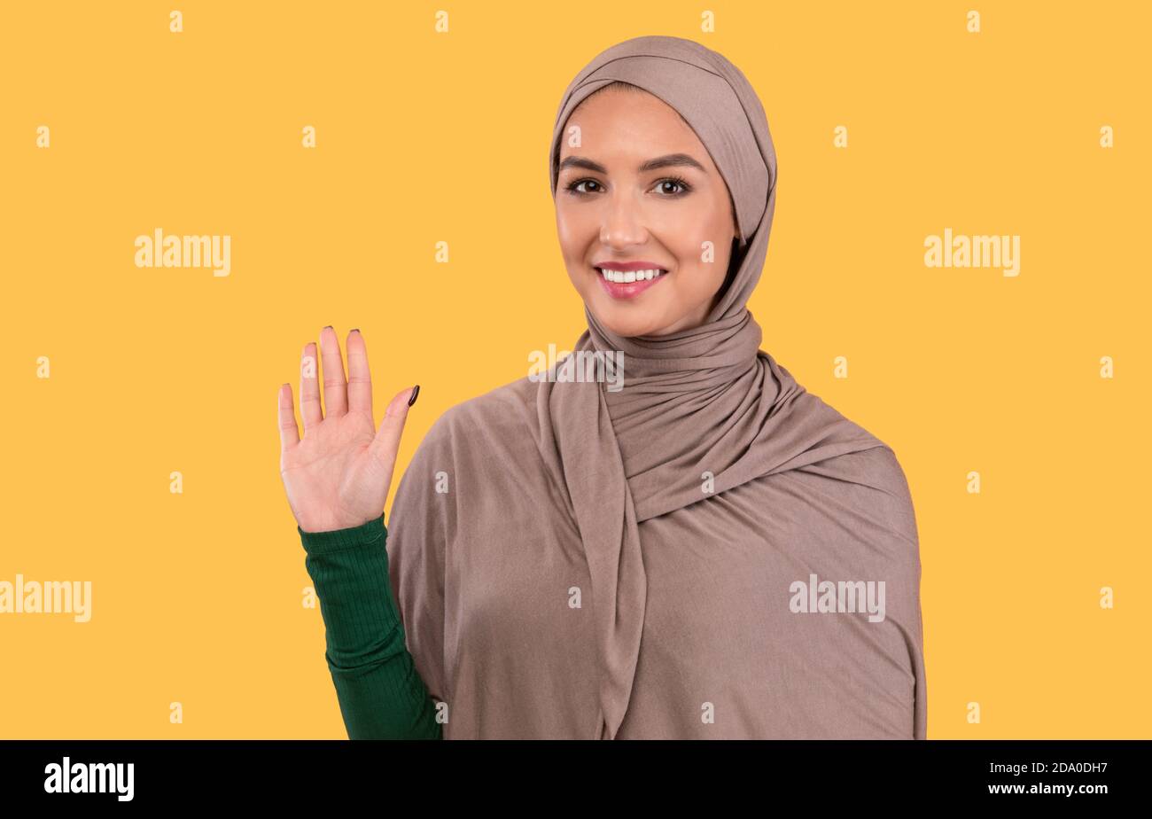 Muslim Lady Waving Hand Gesturing Hello Greeting On Yellow Background ...