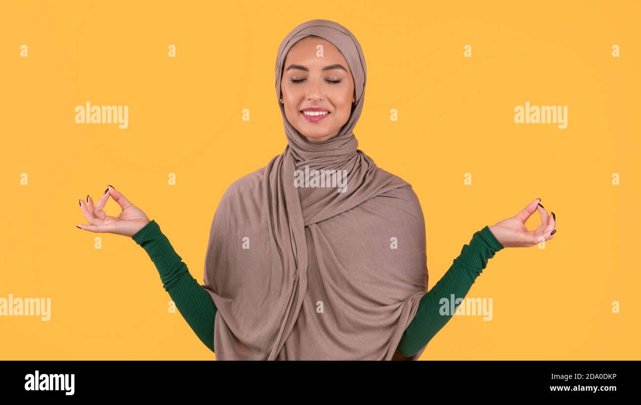 Muslim Woman In Hijab Meditating With Eyes Closed, Yellow Background ...