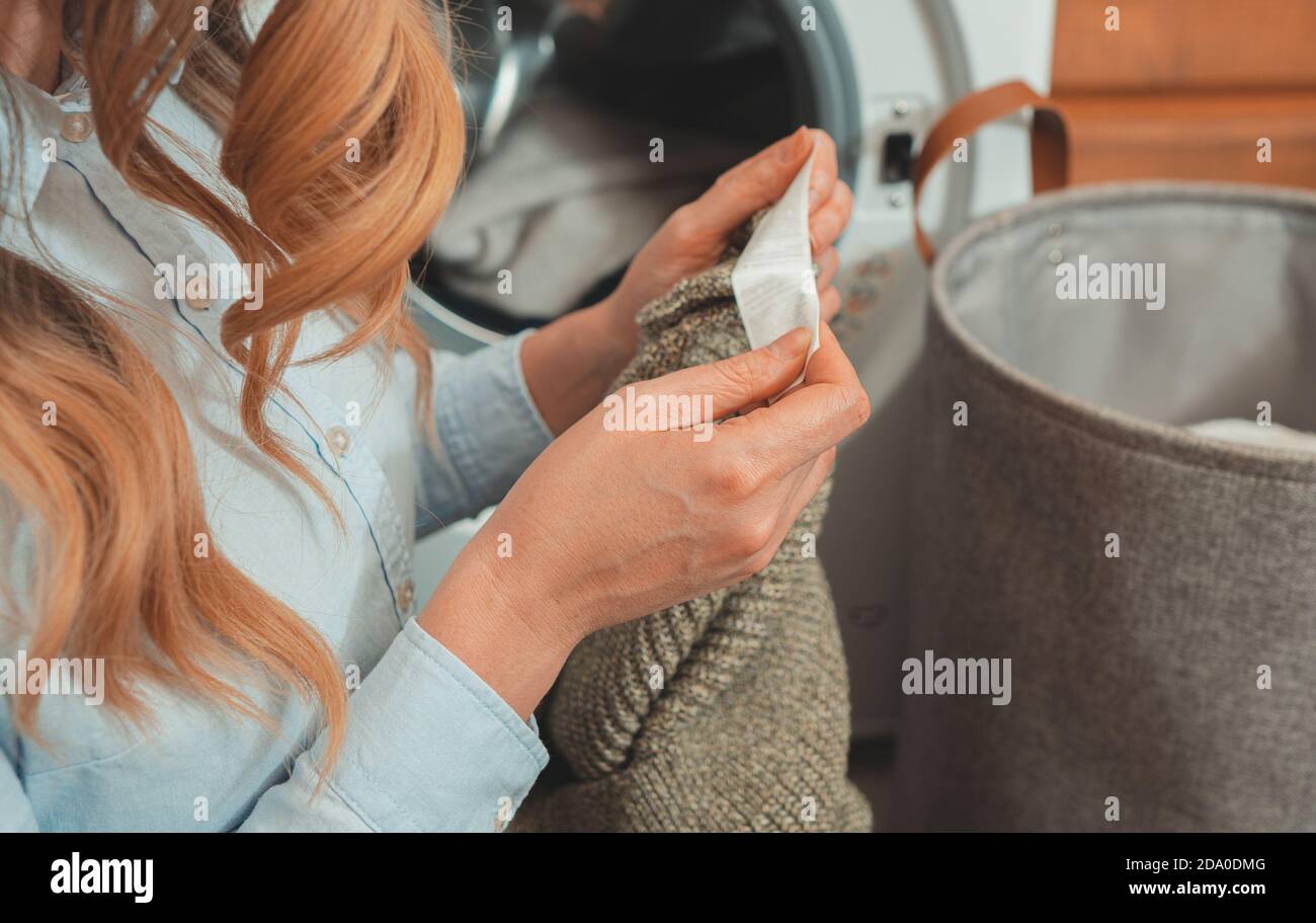 Woman looking at the tag on the clothes before loading clothes into ...
