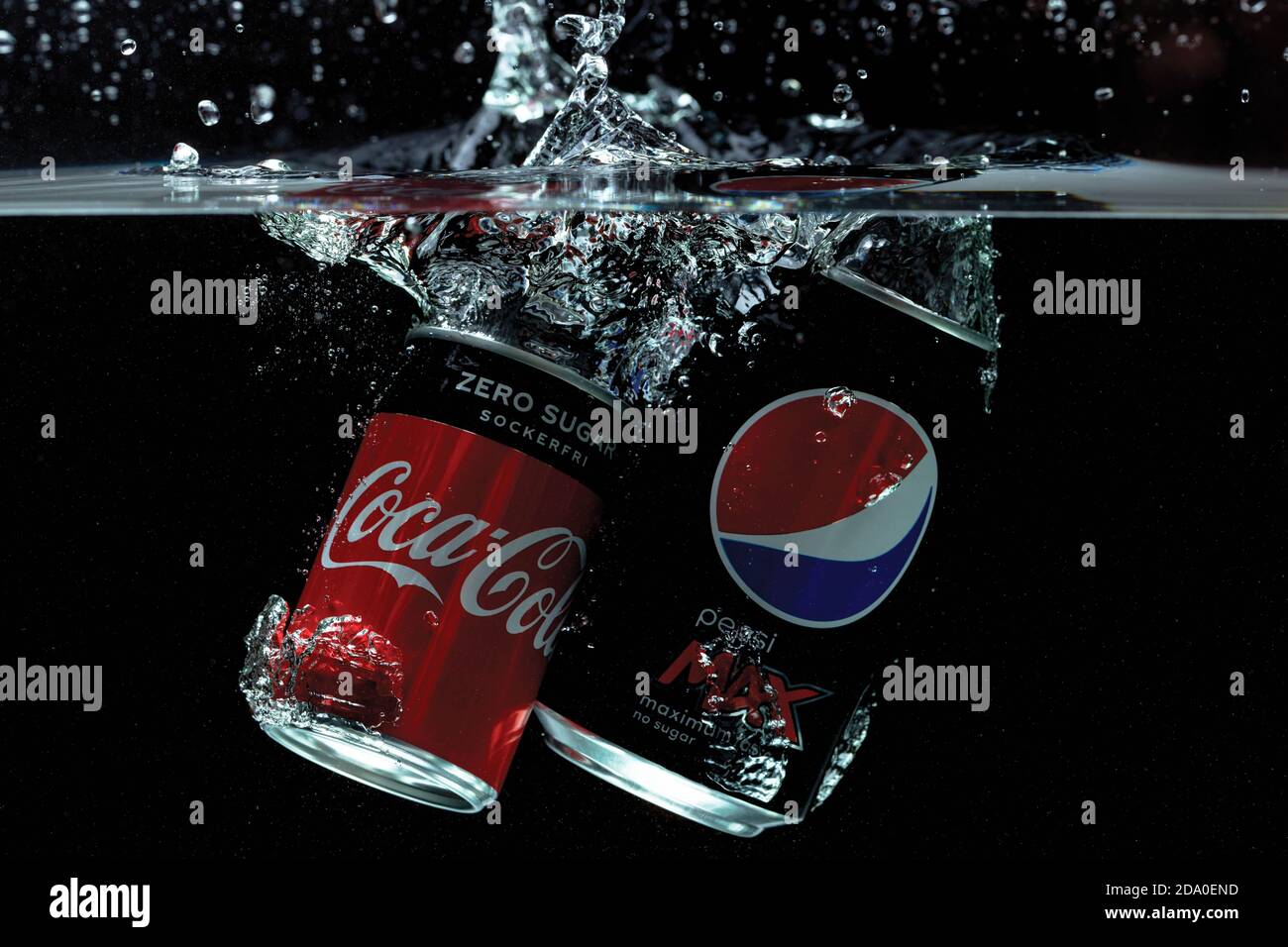 Close up view of coca and pepsi falling in water on black background ...