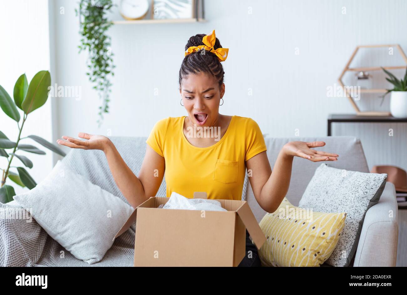Angry black woman unpacking wrong box, delivery mistake Stock Photo - Alamy