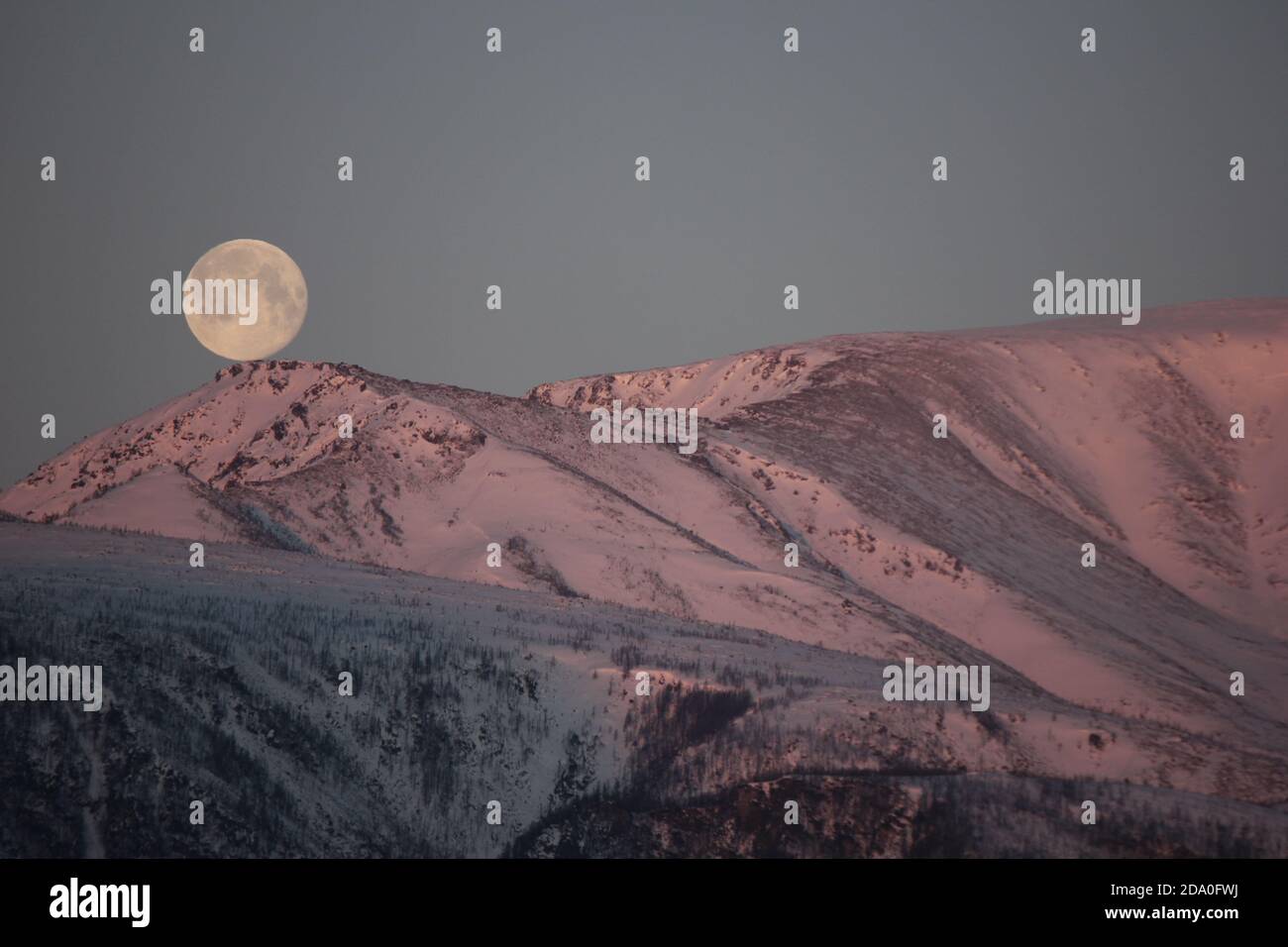 Big moon against the backdrop of snow-capped mountains. Big moon over a ...
