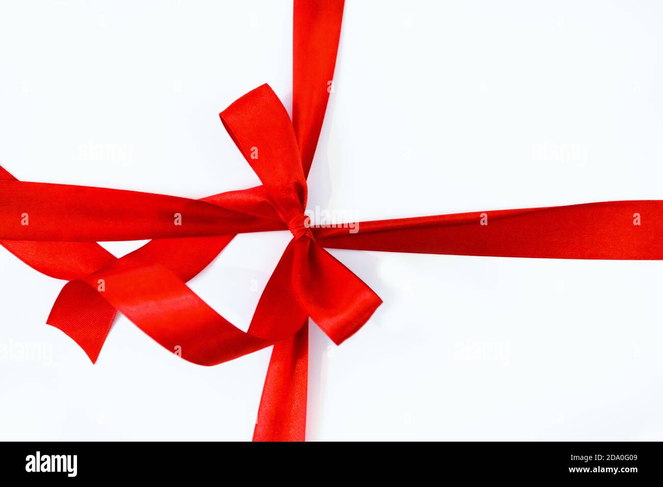 Shiny red satin ribbon tied in a bow on a white background. Selective ...