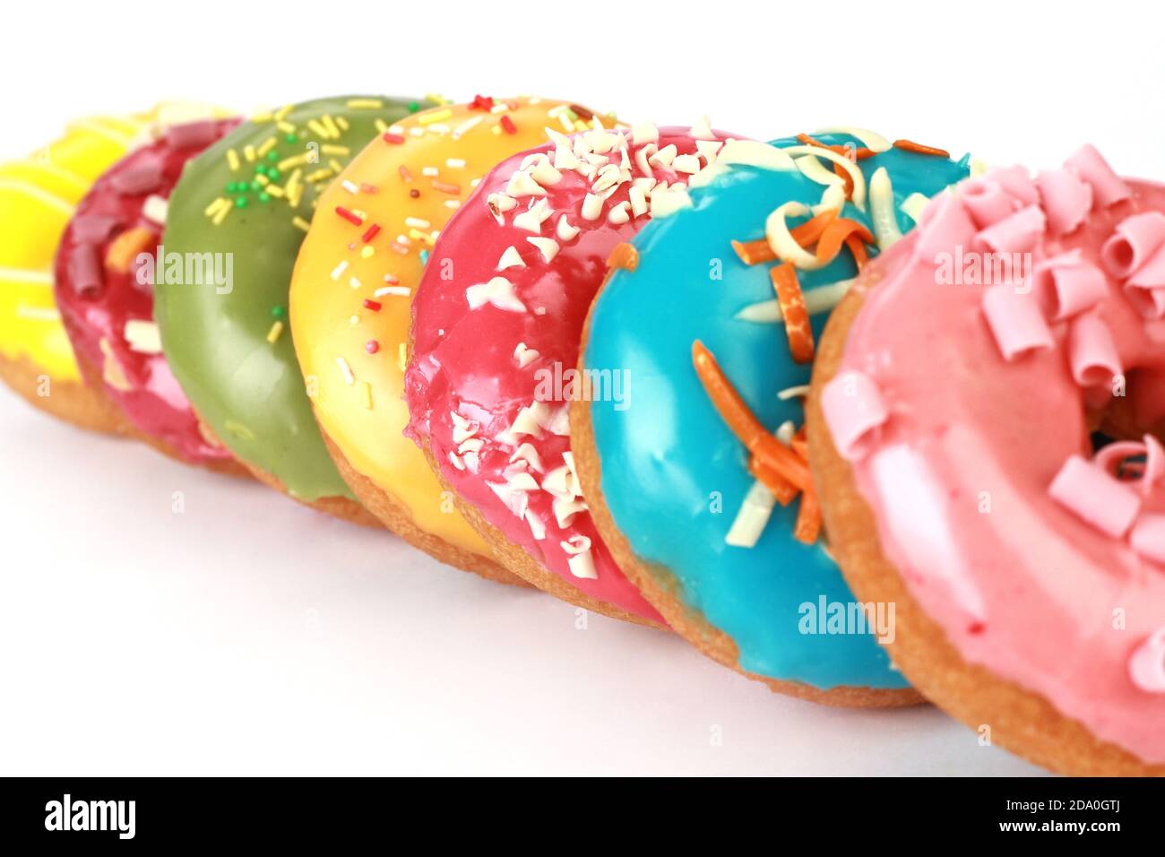 Closeup of a row of colorful glazed doughnuts isolated on white ...
