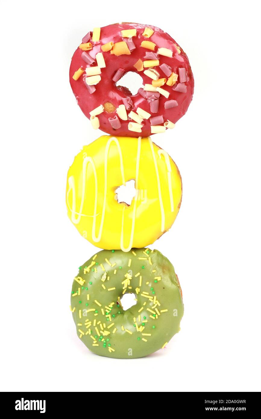 Vertical shot of three colorful glazed doughnuts isolated on white ...