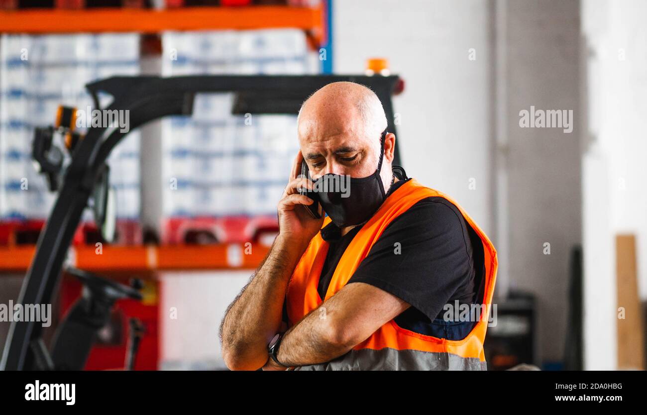 Serious adult male manager in uniform and protective mask standing with ...