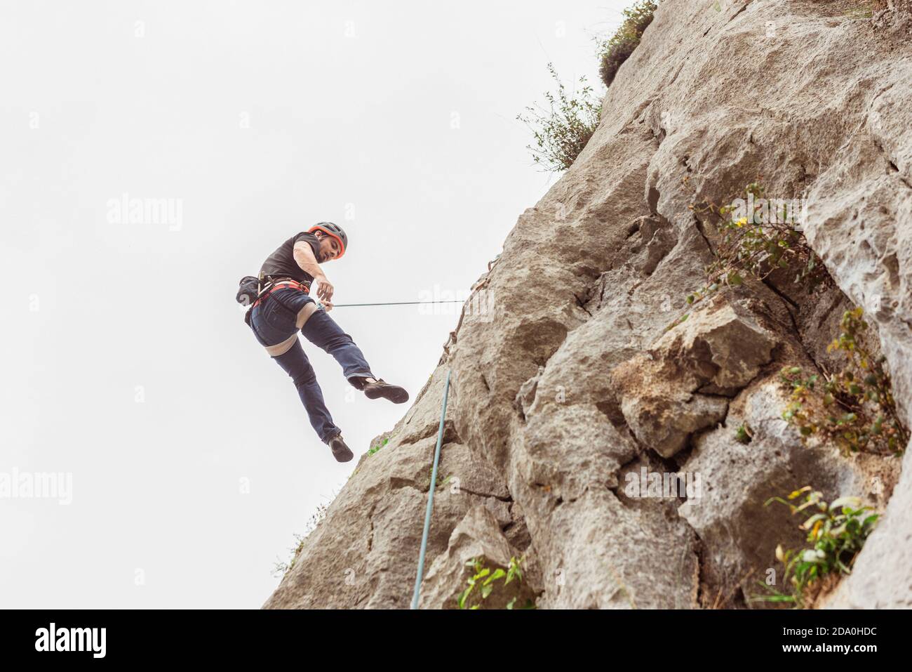 Sportive male alpinist climbing on sheer cliff in summer day Stock ...