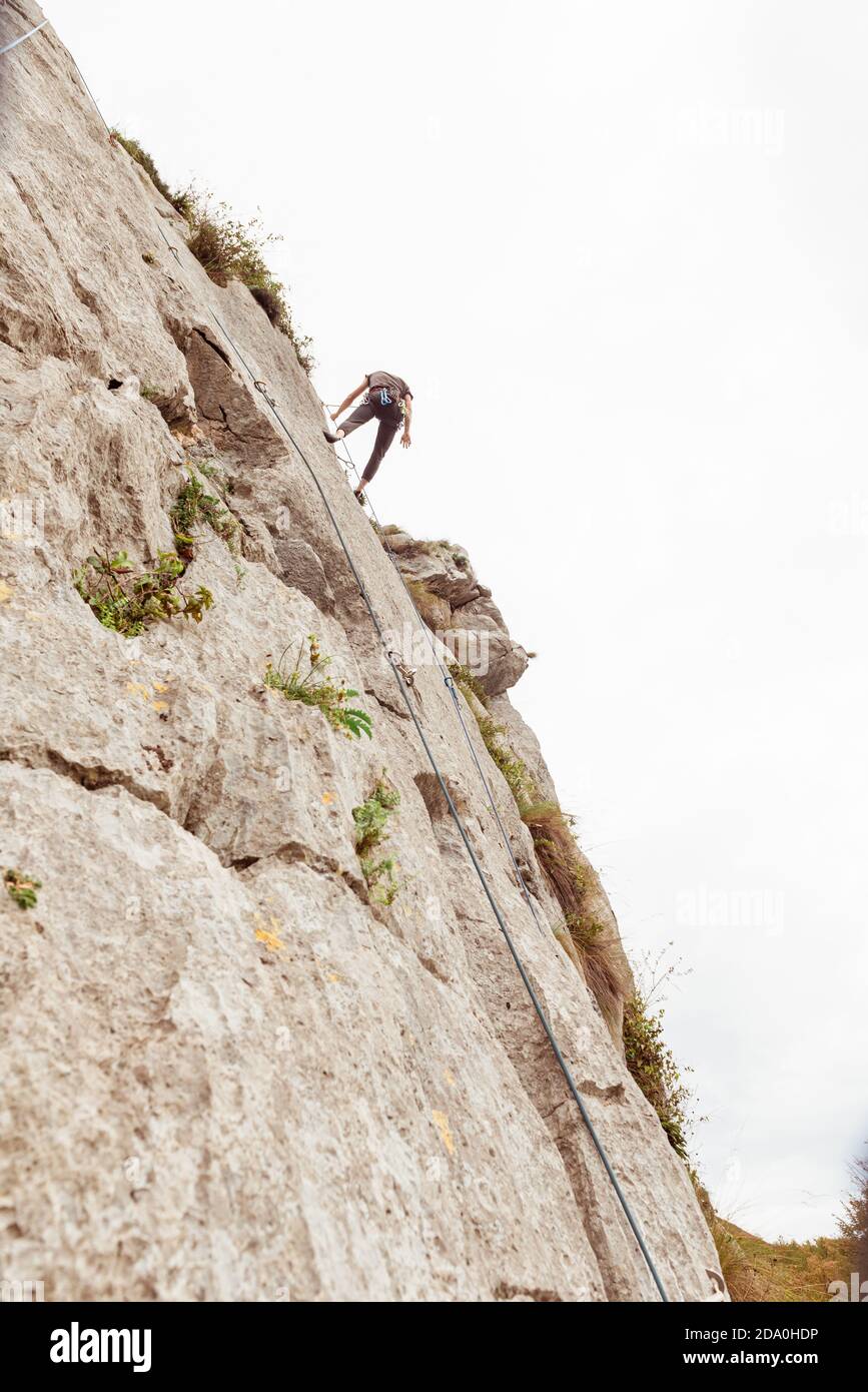 Sportive male alpinist climbing on sheer cliff in summer day Stock ...