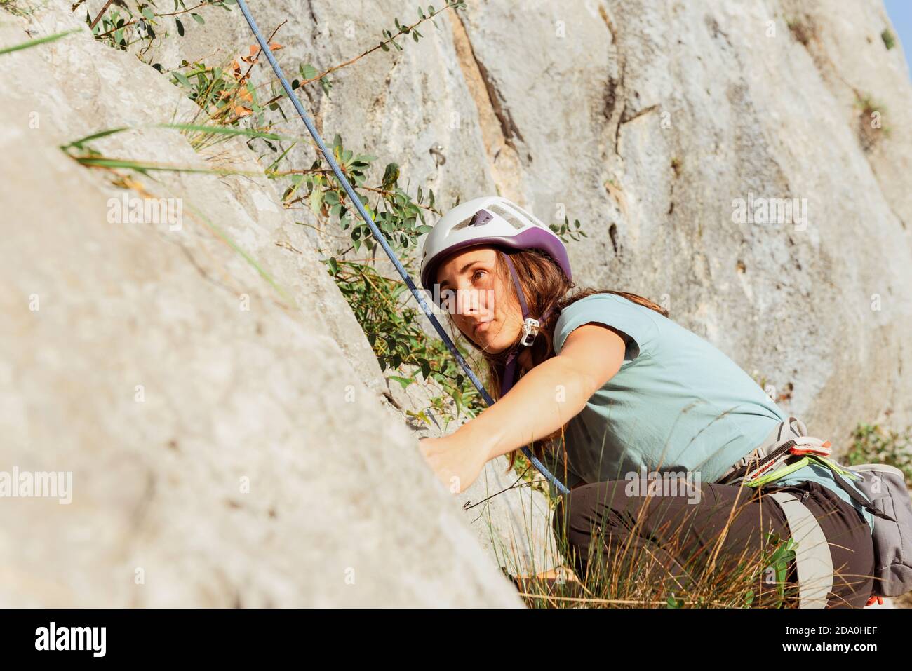 Sportive female alpinist climbing on sheer cliff in summer day Stock ...