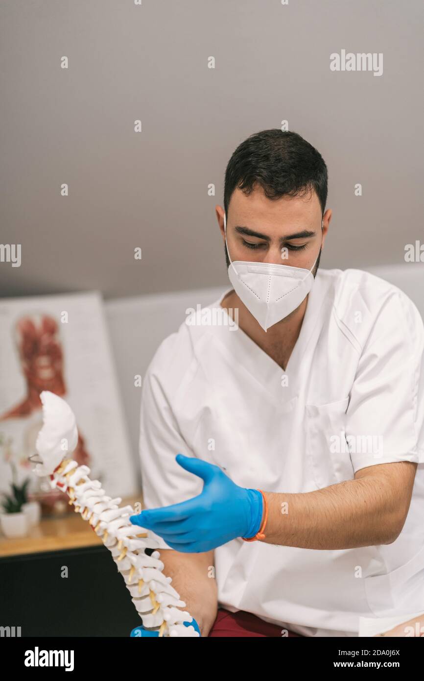 Male physiotherapist explaining spine structure for female patient ...