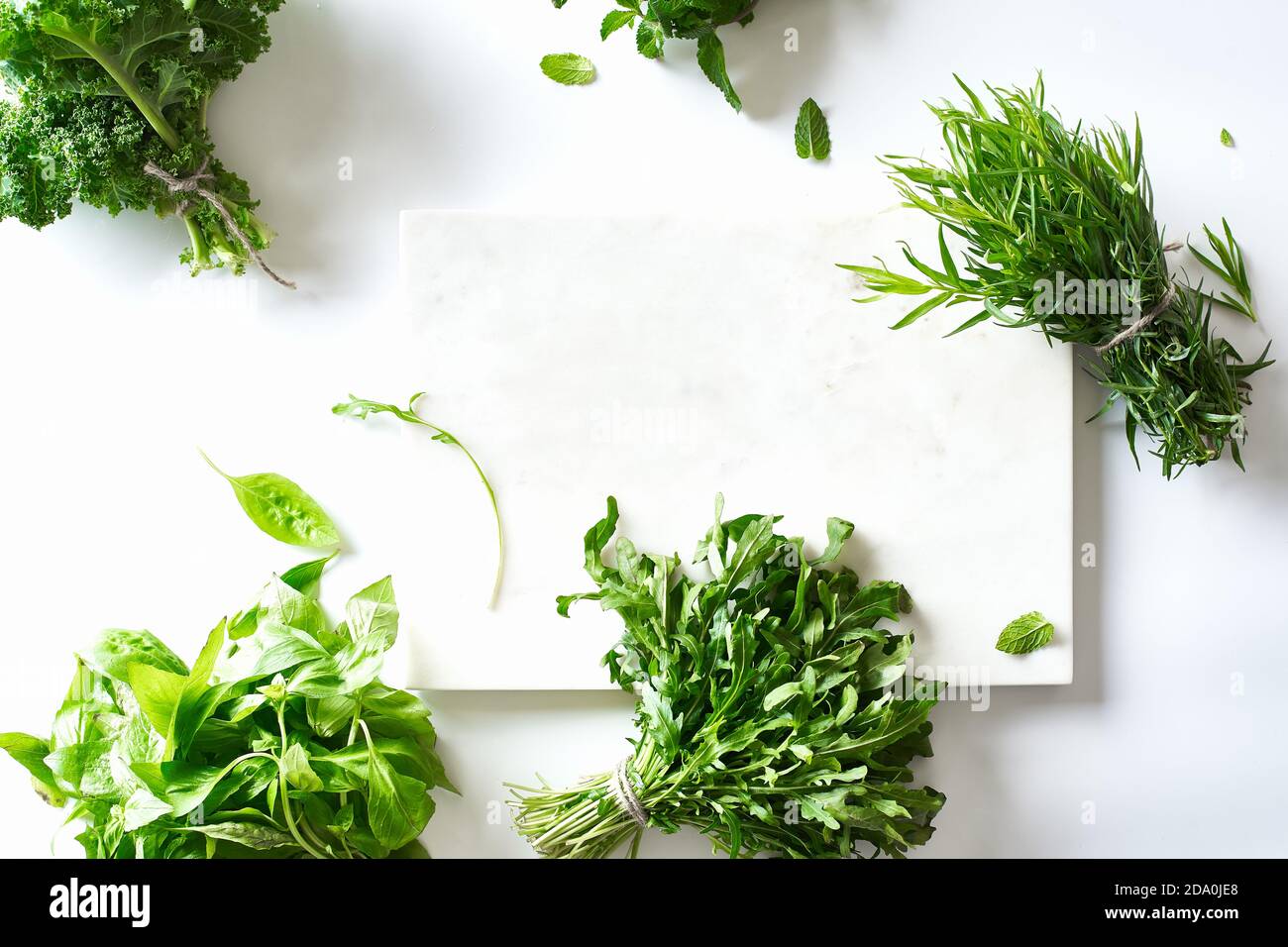 Flat lay with various herbs and lettuce and marble cutting board on ...