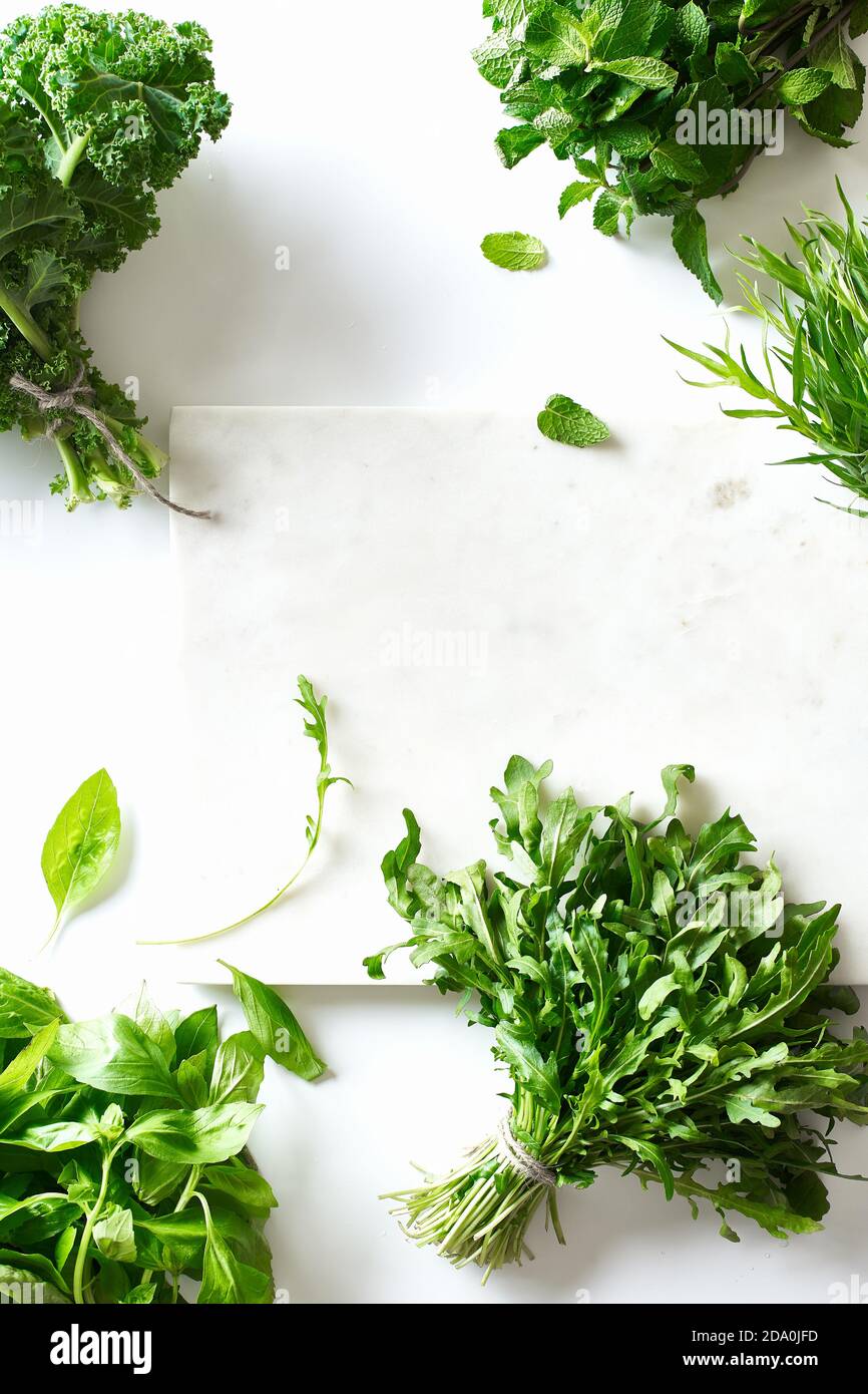Flat lay with various herbs and lettuce and marble cutting board on ...