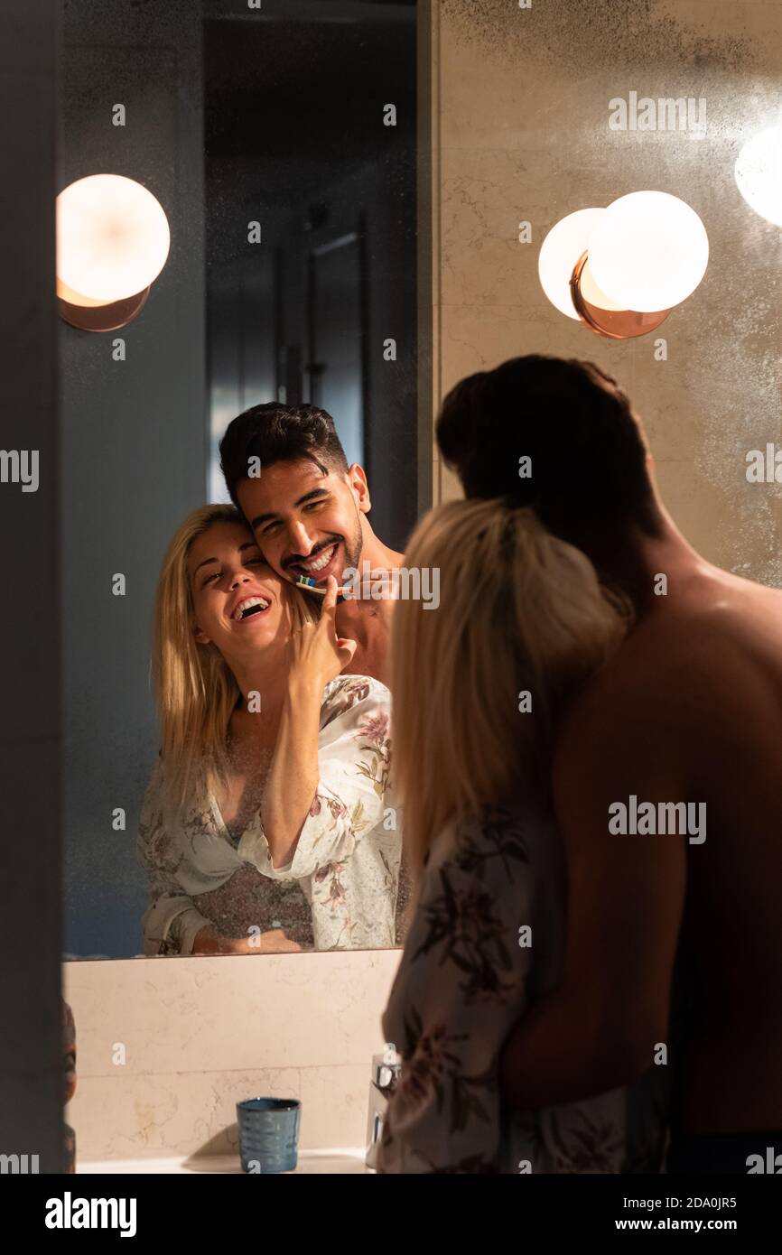 Handsome Bearded Man Hugging Cheerful Girlfriend While Brushing Teeth