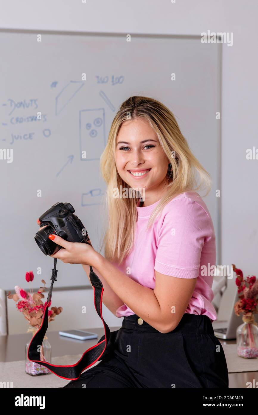 Side view of optimistic female photographer with professional camera ...