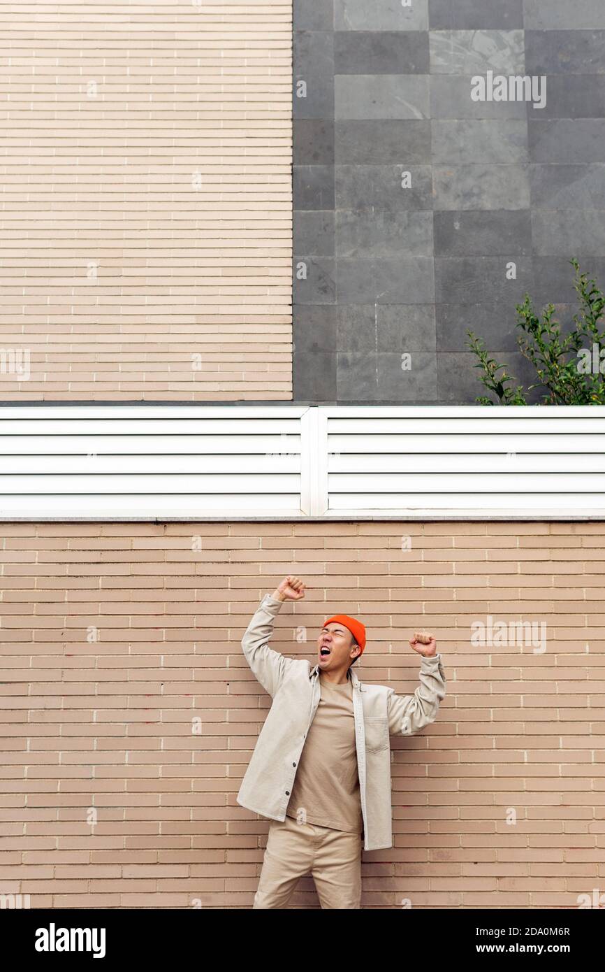 Overwhelmed male in casual outfit yelling and lifting fists in ...