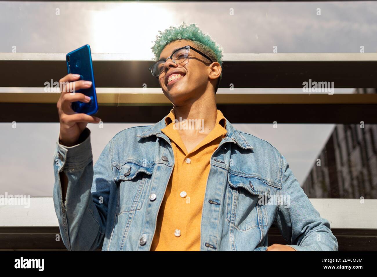 From below of cheerful African American male hipster with blue hair ...