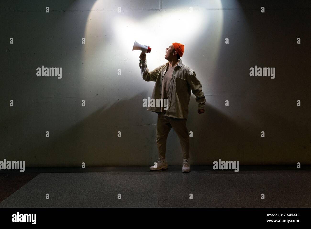 Full body overwhelmed male in casual clothes screaming in loudspeaker ...