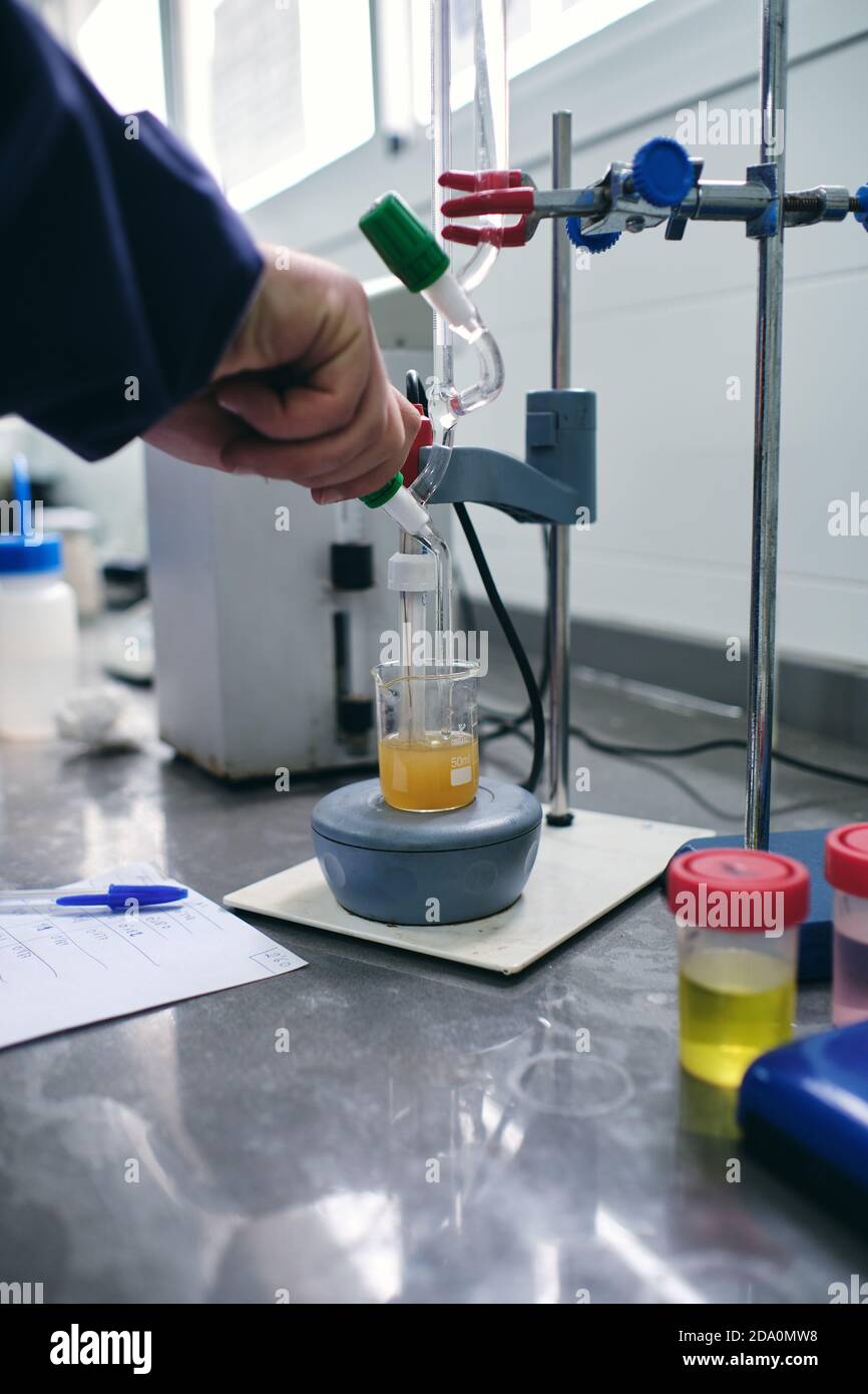 Hand of unrecognizable male chemist pouring liquid into flask while ...