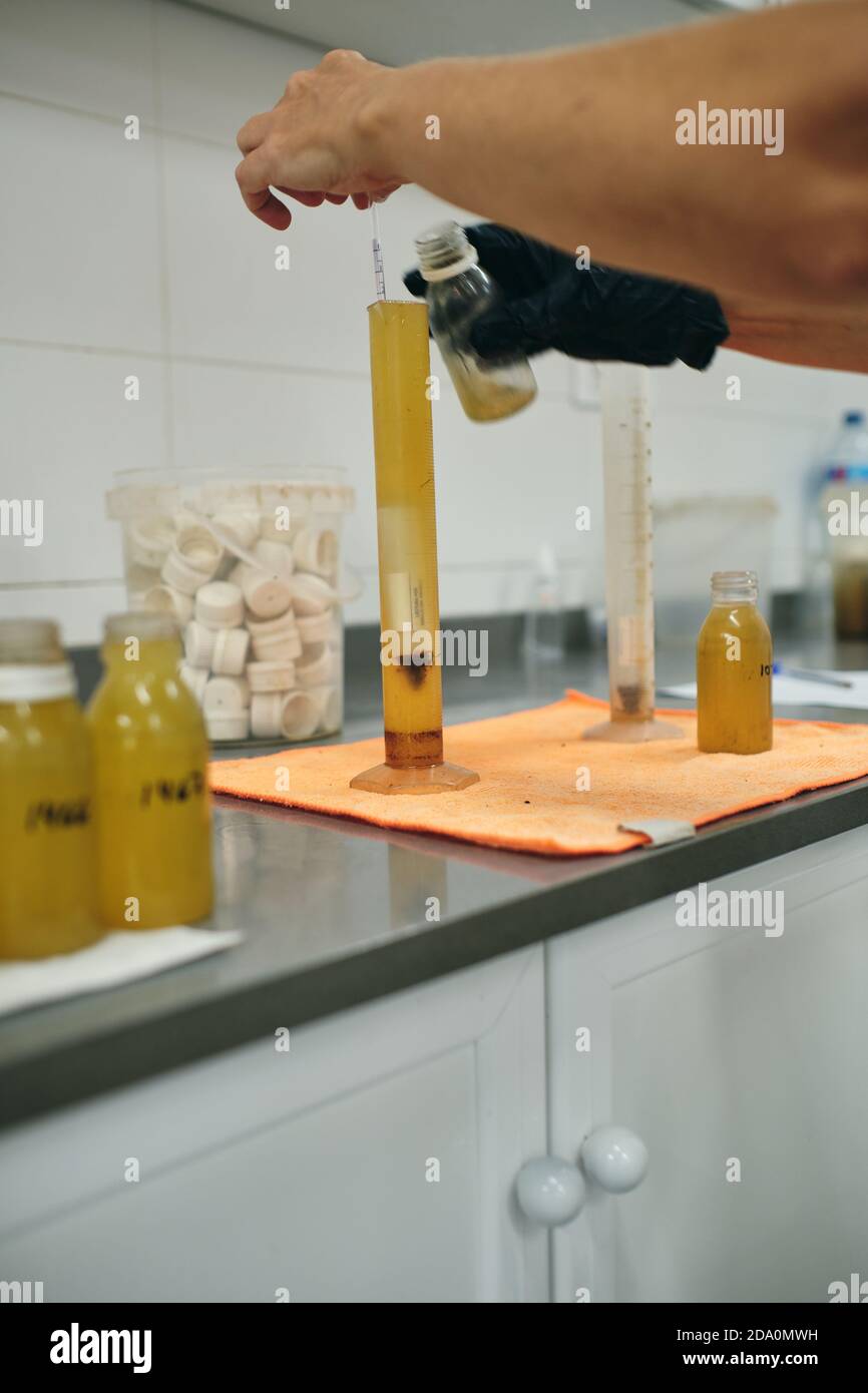 Unrecognizable crop chemist pouring yellow liquid in tube placed on ...