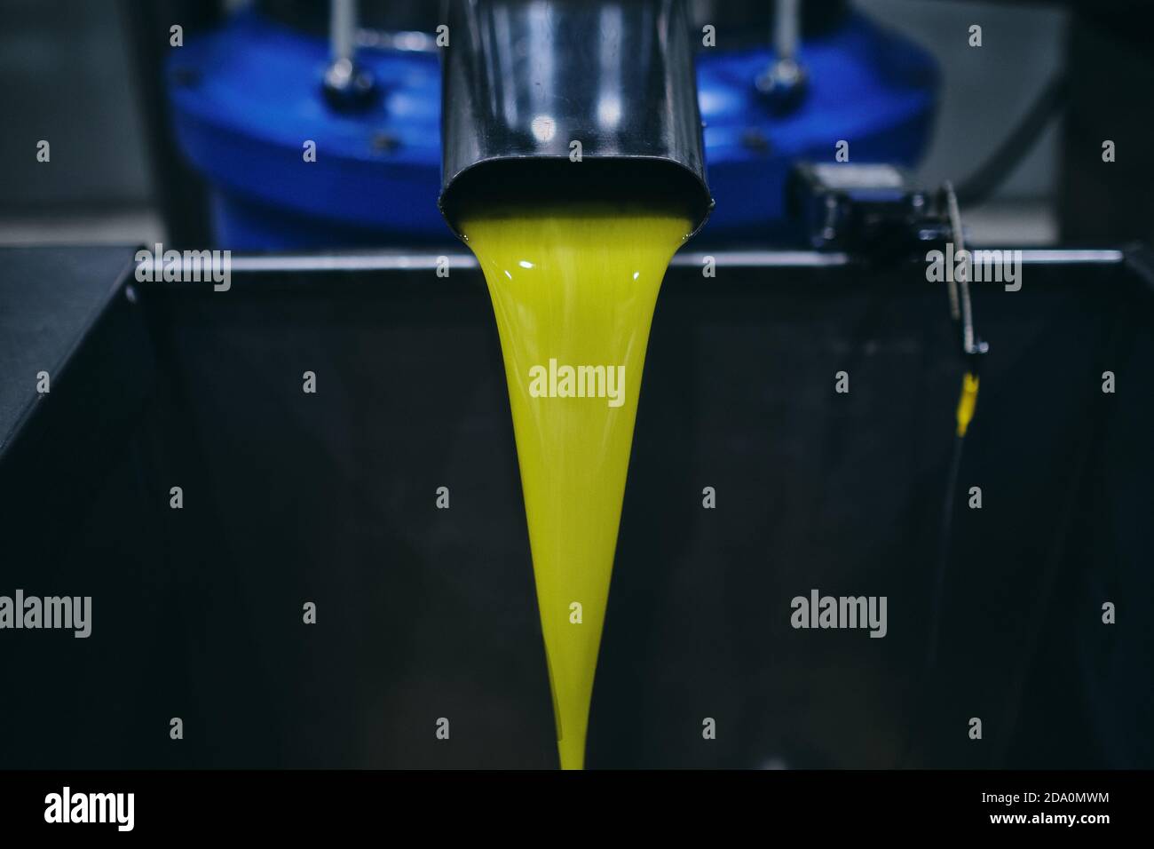 Closeup of yellow chemical liquid flowing from metal tap in industrial ...